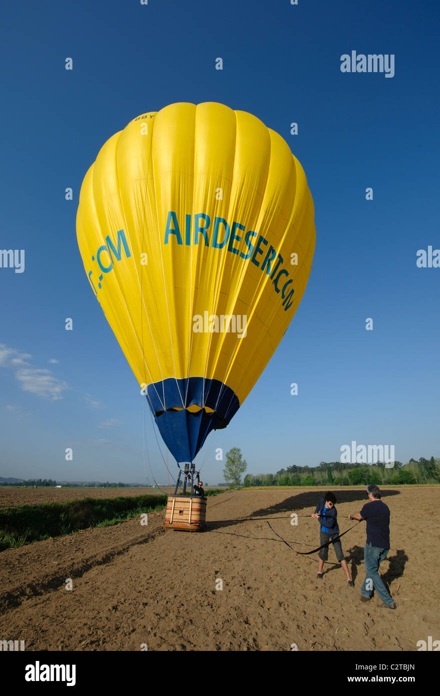 People pulling an hot air balloon after landing in a field Stock Photo ...