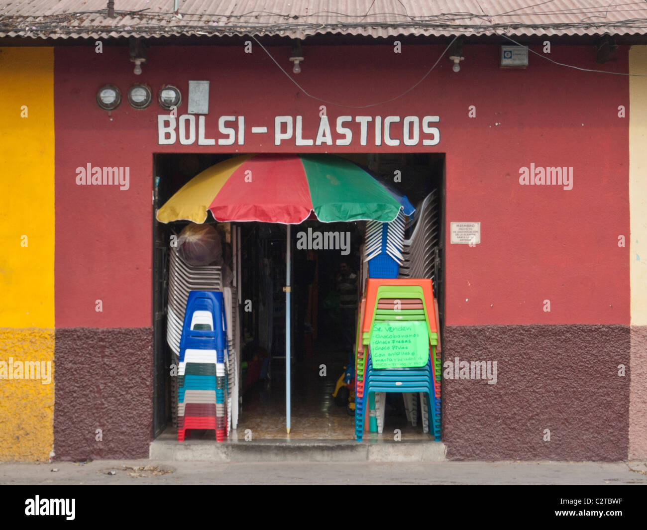 Terra cotta and brown painted store front with bright plastic chairs ...