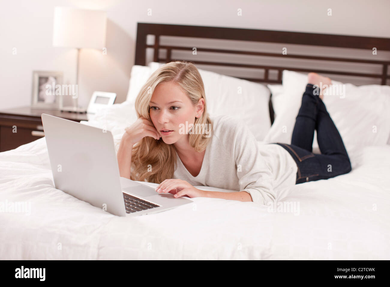 Women laying on bed using laptop Stock Photo - Alamy