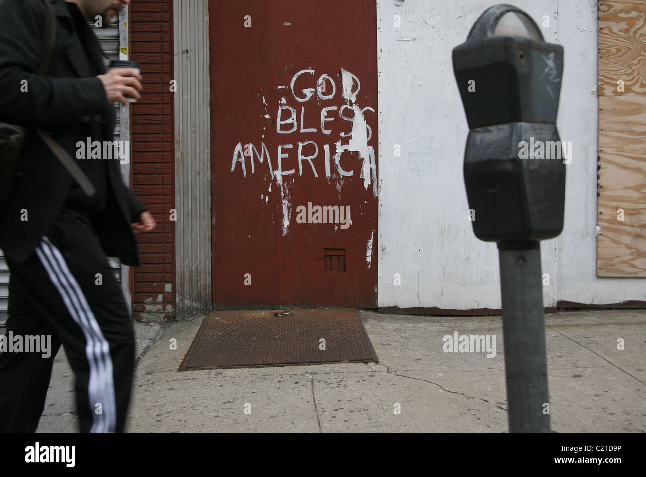 Man walking past 'God Bless America' graffiti on wall Stock Photo - Alamy
