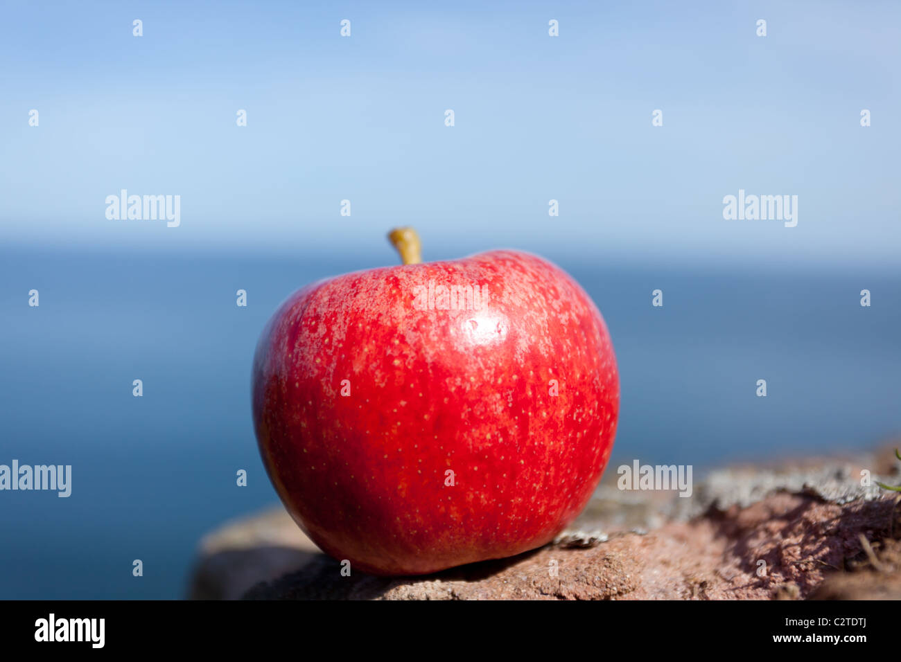 A bright red apple in front of a beautiful blue sky Stock Photo - Alamy
