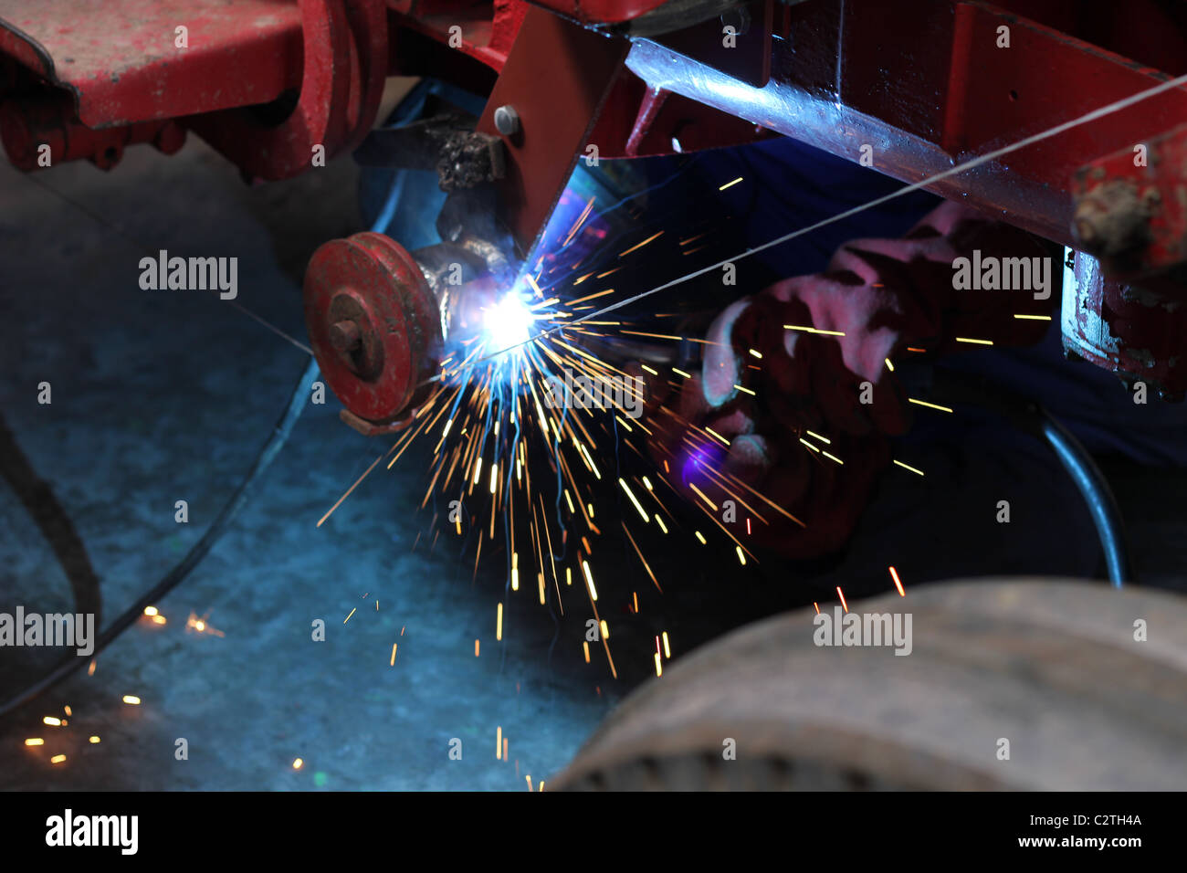 Engineer Welding underneath Tractor Stock Photo - Alamy