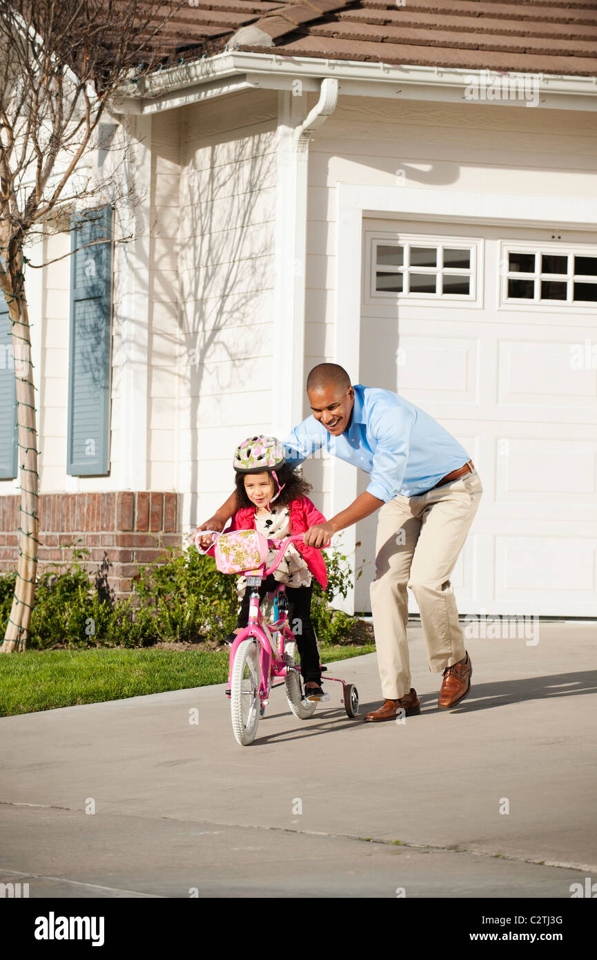 Father helping daughter learn to ride a bike Stock Photo - Alamy