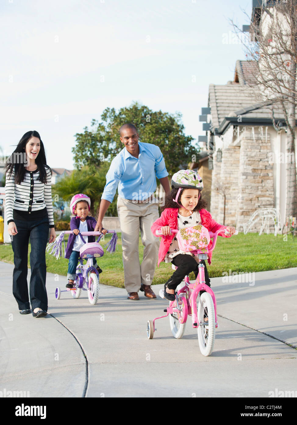Parents watching children ride bicycles Stock Photo - Alamy