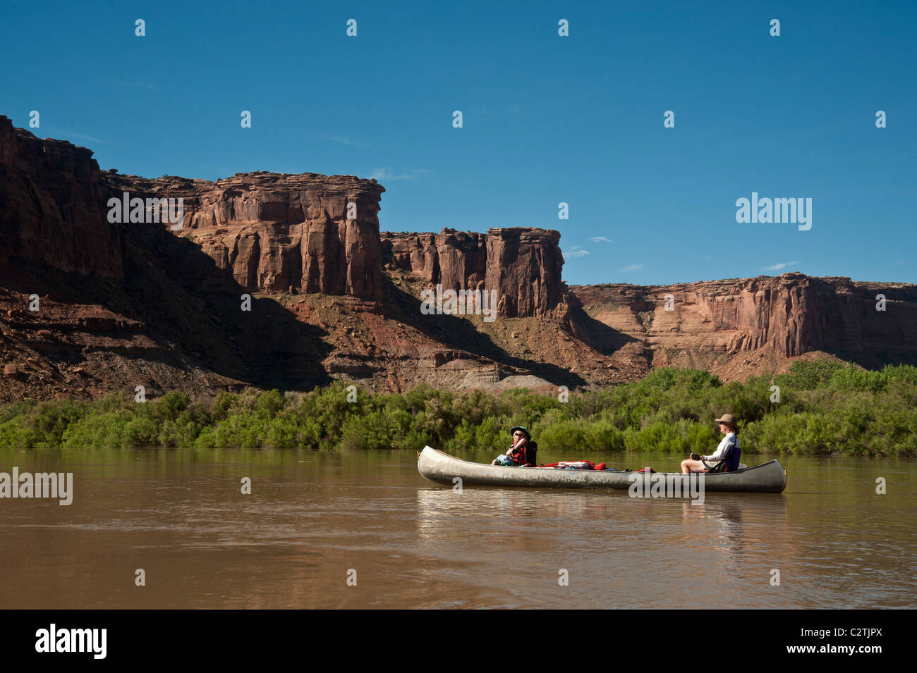Mother and daughter canoeing on a calm blue river in the desert country ...