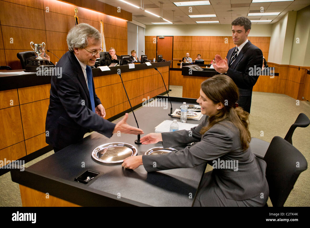 A happy student receives a prize in the moot court from the dean of the ...