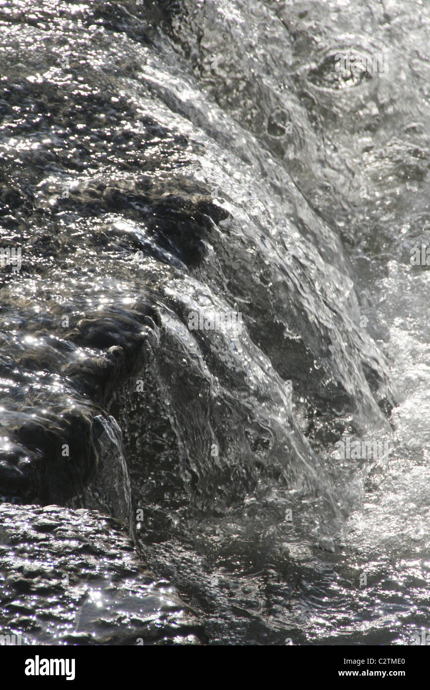 close up detail of fast moving waterfall in river in sun Stock Photo ...