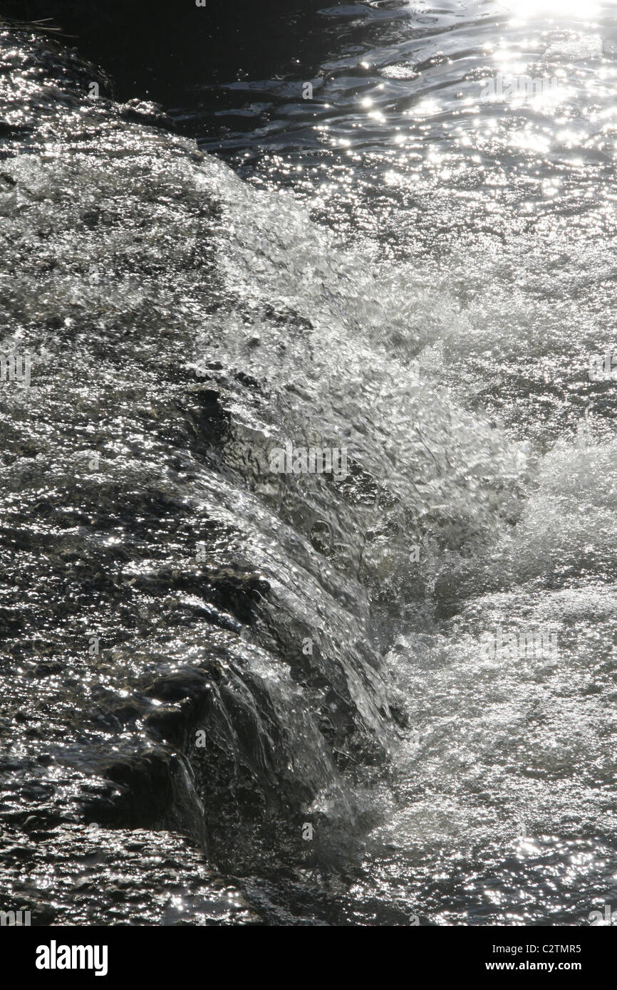 close up detail of fast moving waterfall in river in sun Stock Photo ...