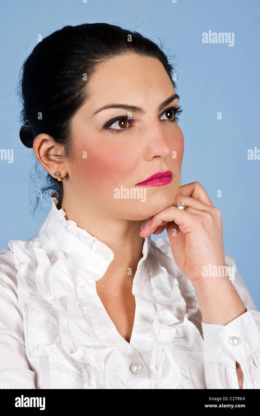 Beautiful thinking woman standing with hand to chin and looking away ...