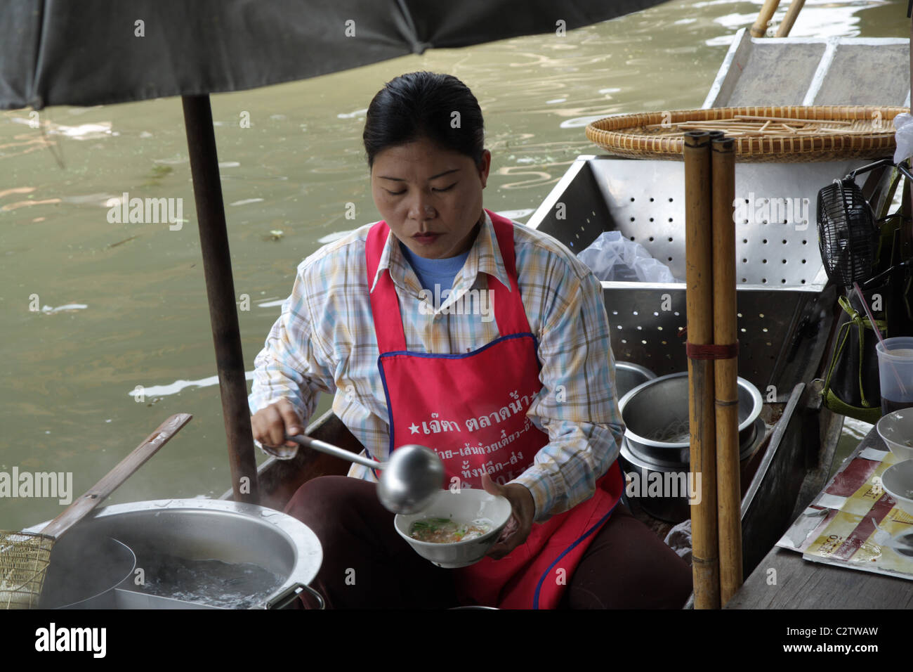 Merchant prepares cooking Thai noodle at Damnoen Saduak Floating Market ...
