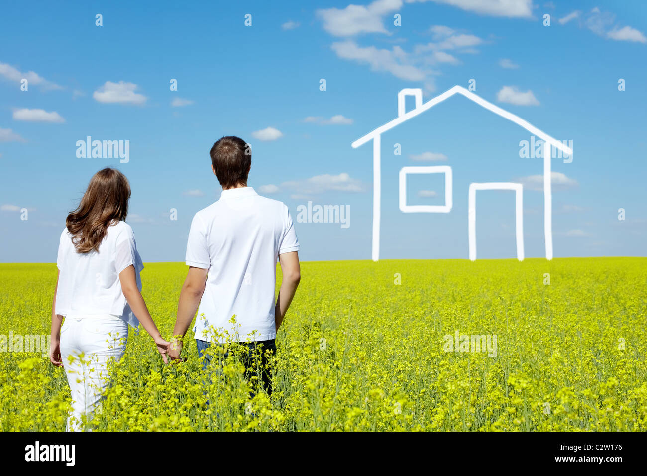 Back view of amorous couple in yellow meadow looking at drawn house ...