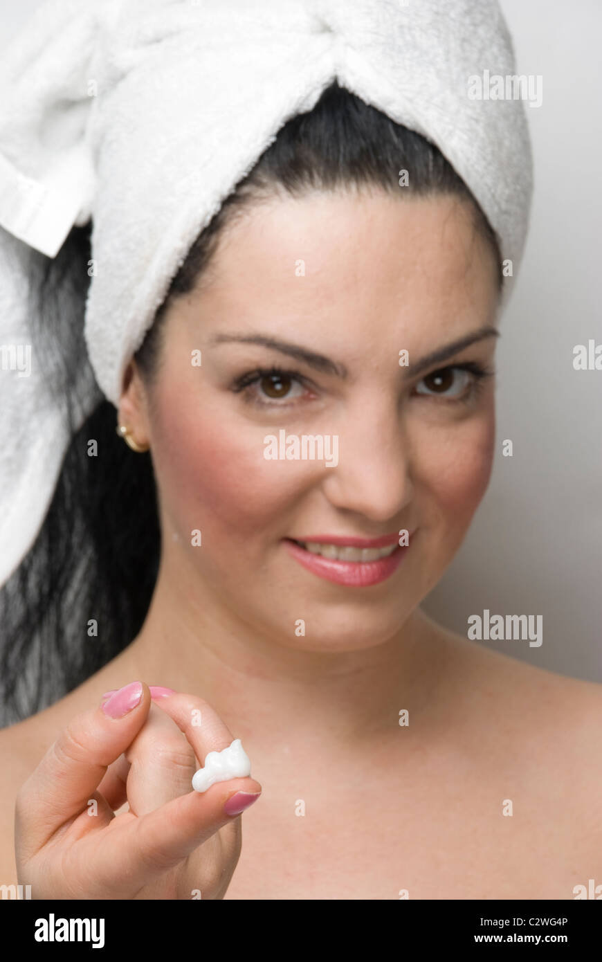 Portrait of young smiling woman showing a finger with cream for skin ...