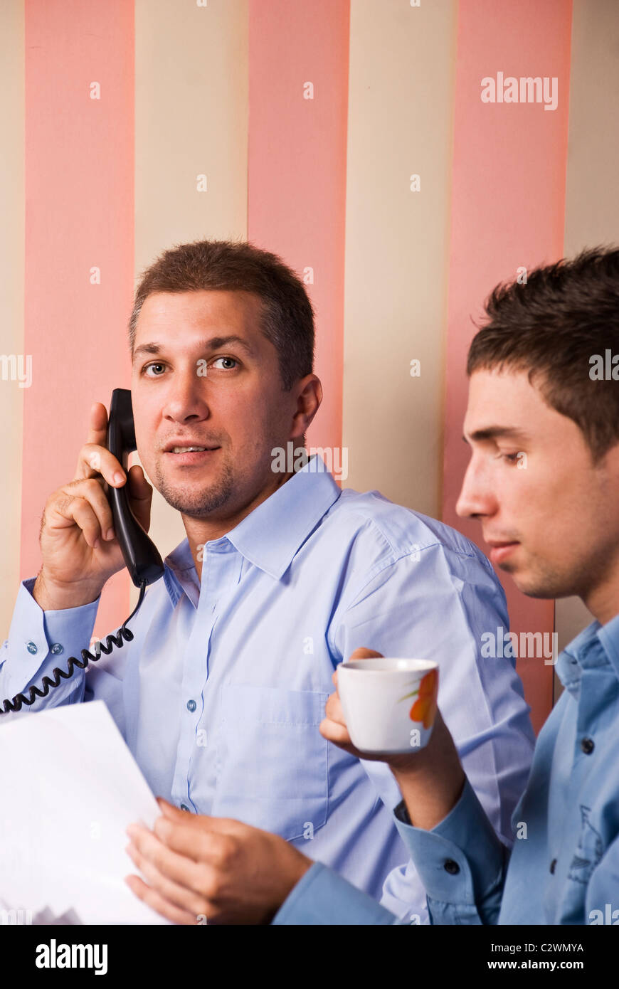 Two business men in office,one man speaking at phone and the other ...