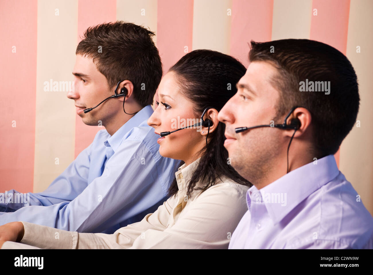 Three office workers working in a call center and sitting on chair in ...