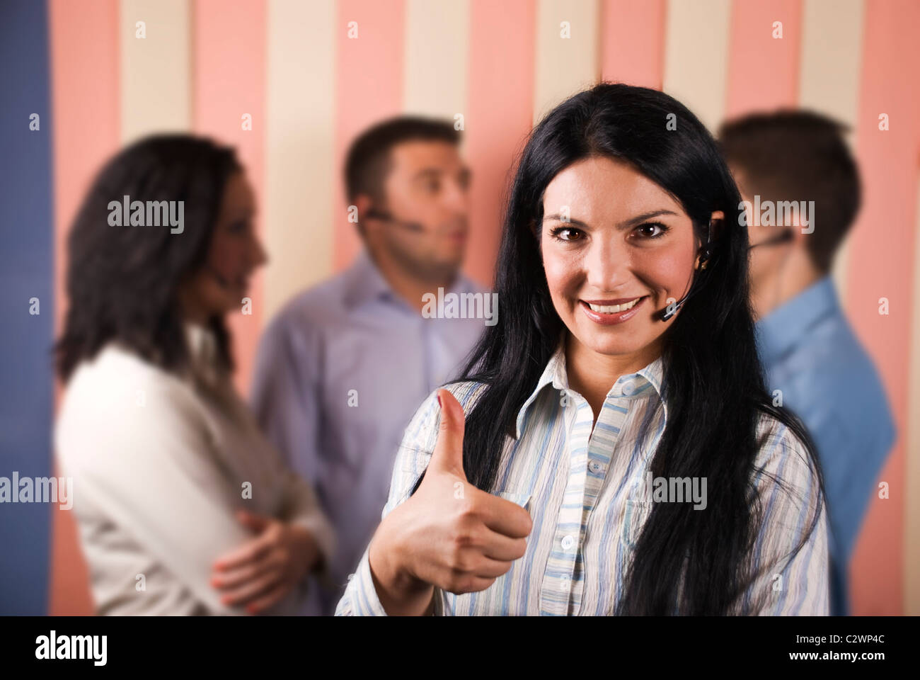 Happy customer service rep smiling and giving thumbs up in front of ...