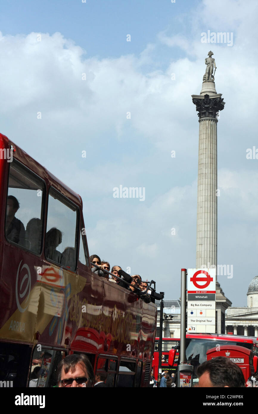 A tour bus full of sightseers, by a bus stop, with Nelson's Column in ...