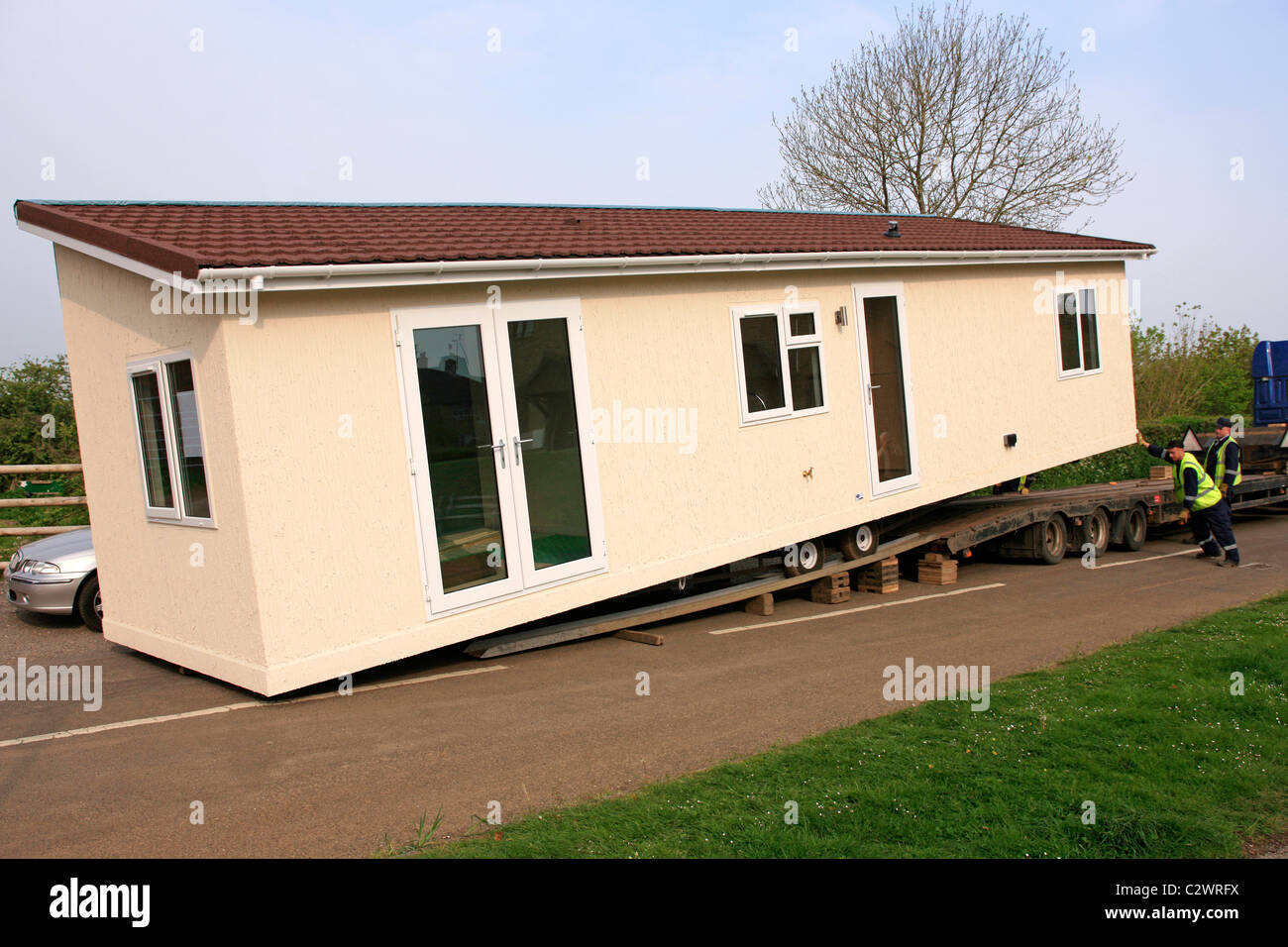 A Low-Loader truck carrying a mobile home starts to unload half of a ...