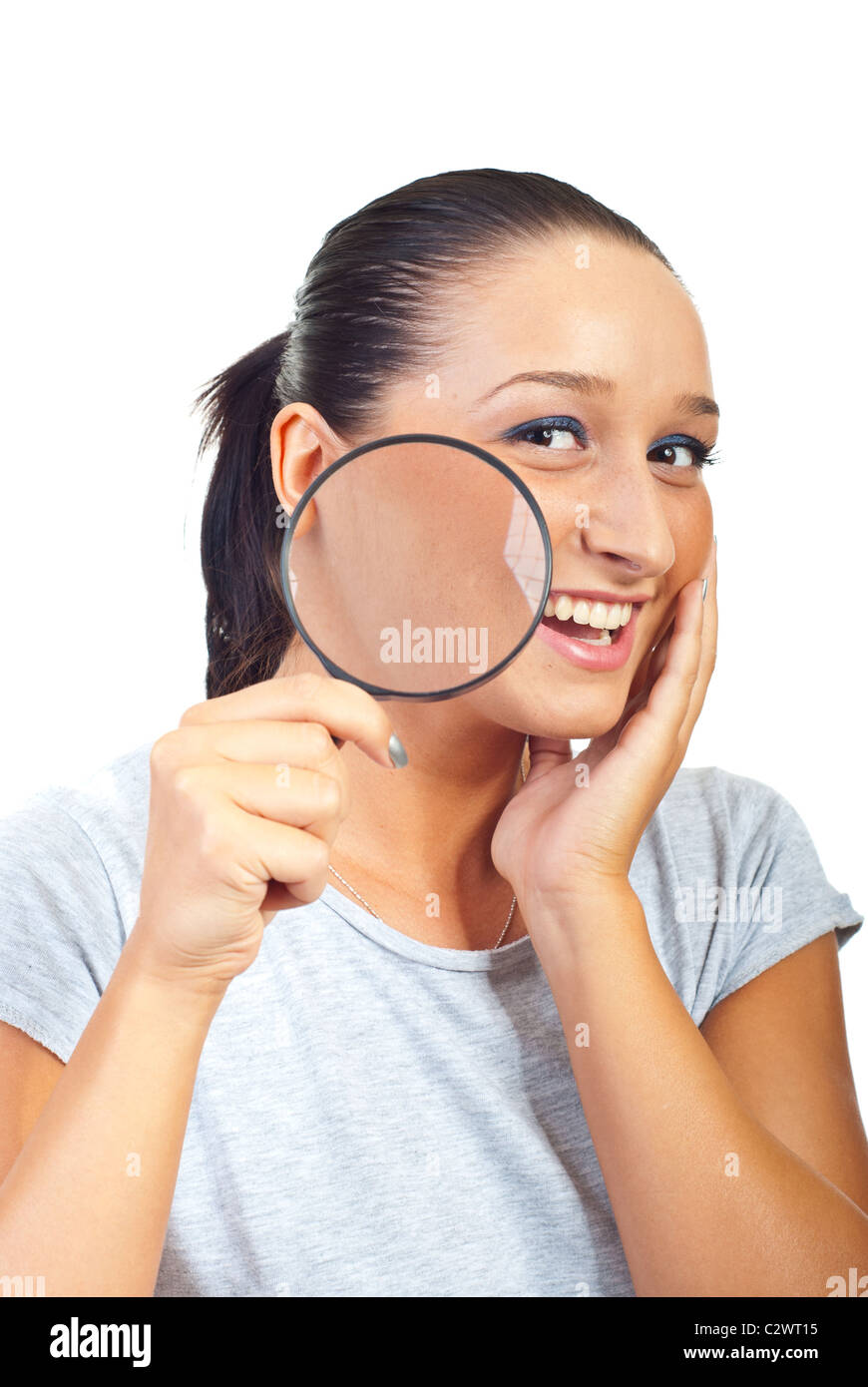 Smiling woman holding magnifying glass close to her healthy face skin ...