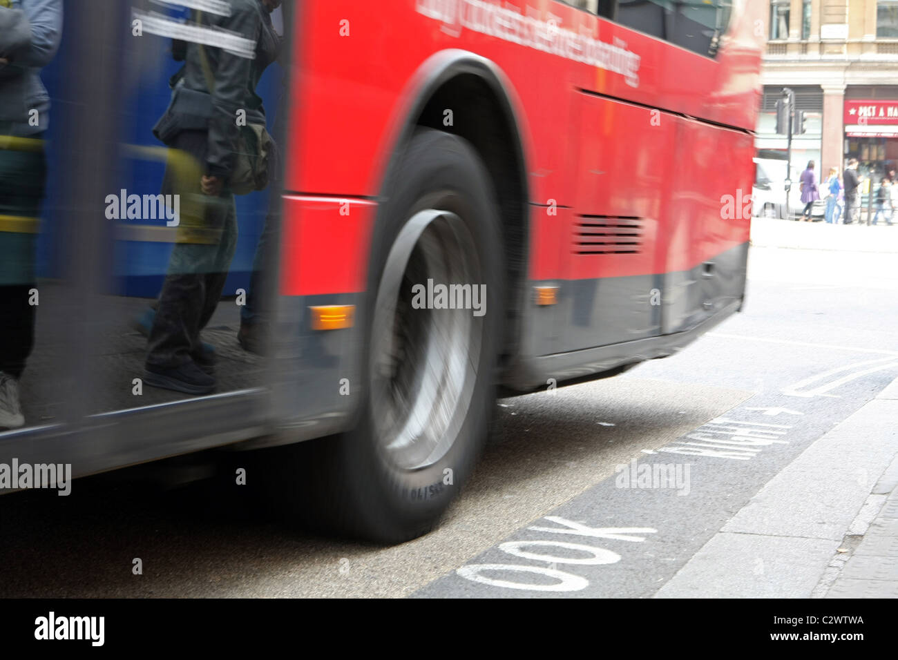 The rear wheel of a double decker red London bus traveling along a road ...
