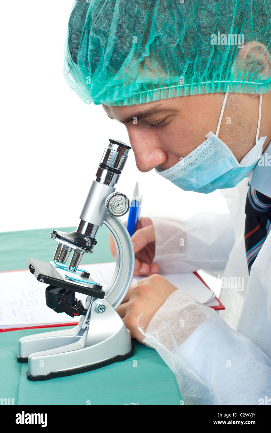Close up of man looking through microscope and taking notes in ...