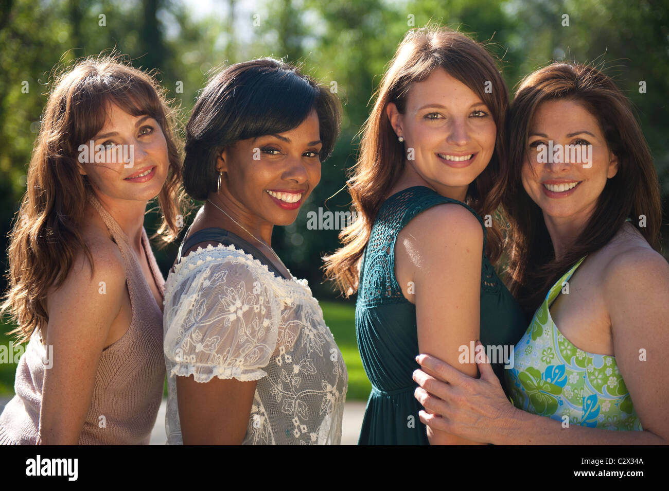 Four attractive affluent women black caucasian look back at camera ...