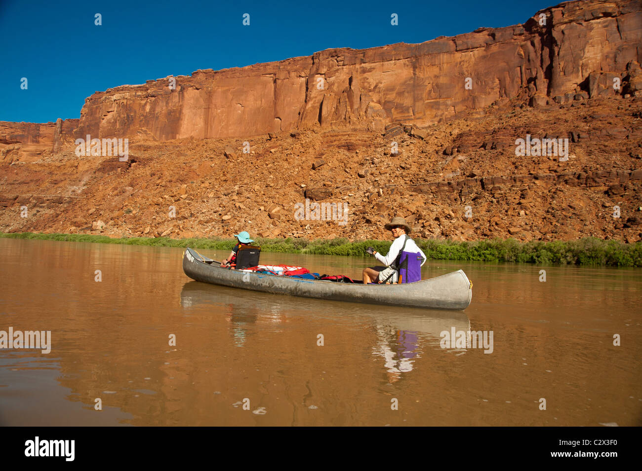 Mother and daughter canoeing on a calm blue river in the desert country ...