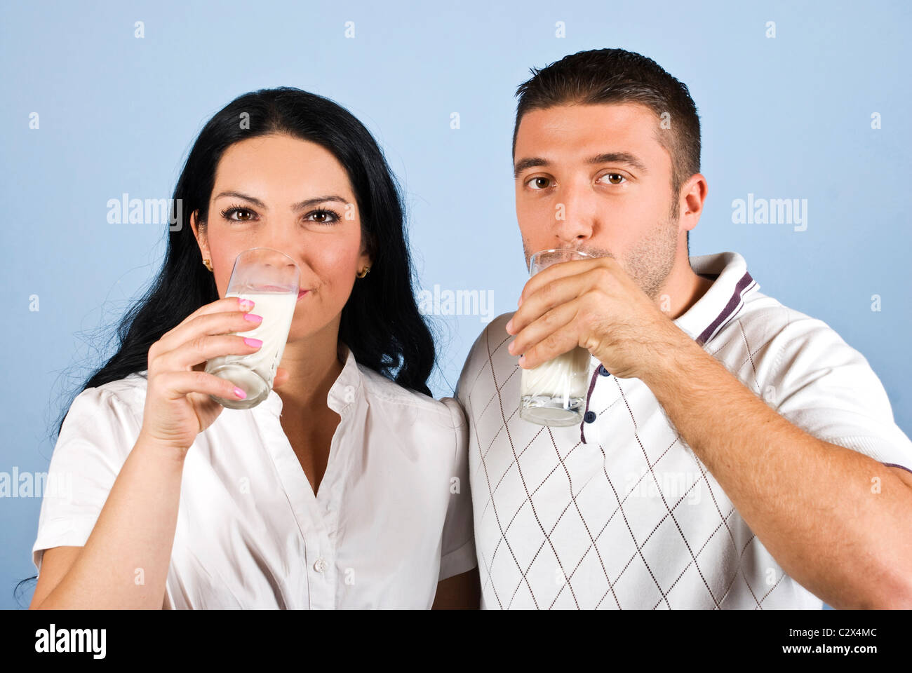 Cheerful healthy couple drinking milk in front of image,they wear white ...
