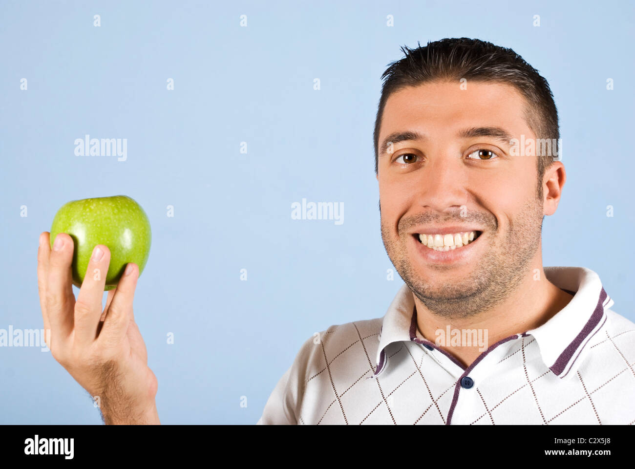Man holding an apple in his hand,smiling and looking camera on blue ...