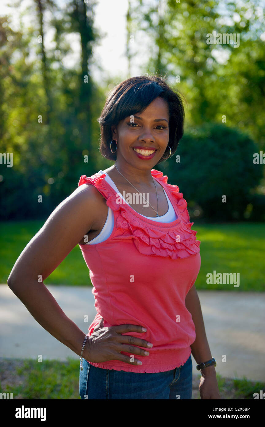 Affluent African American woman in her 30s smiling, hand on waist, next ...