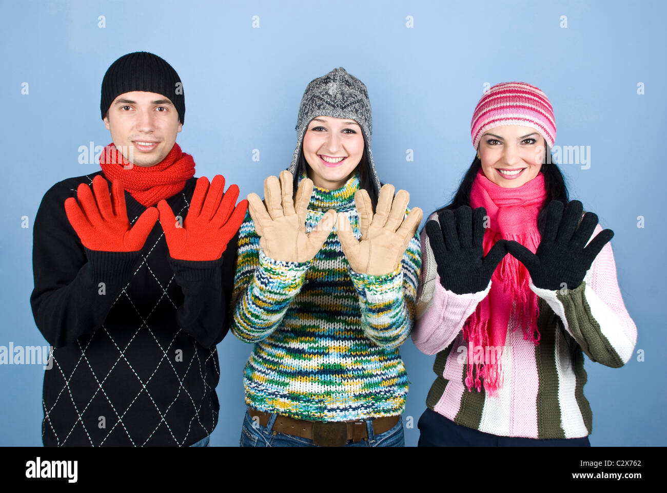 Happy friends in winter clothes standing in a line showing their palms ...