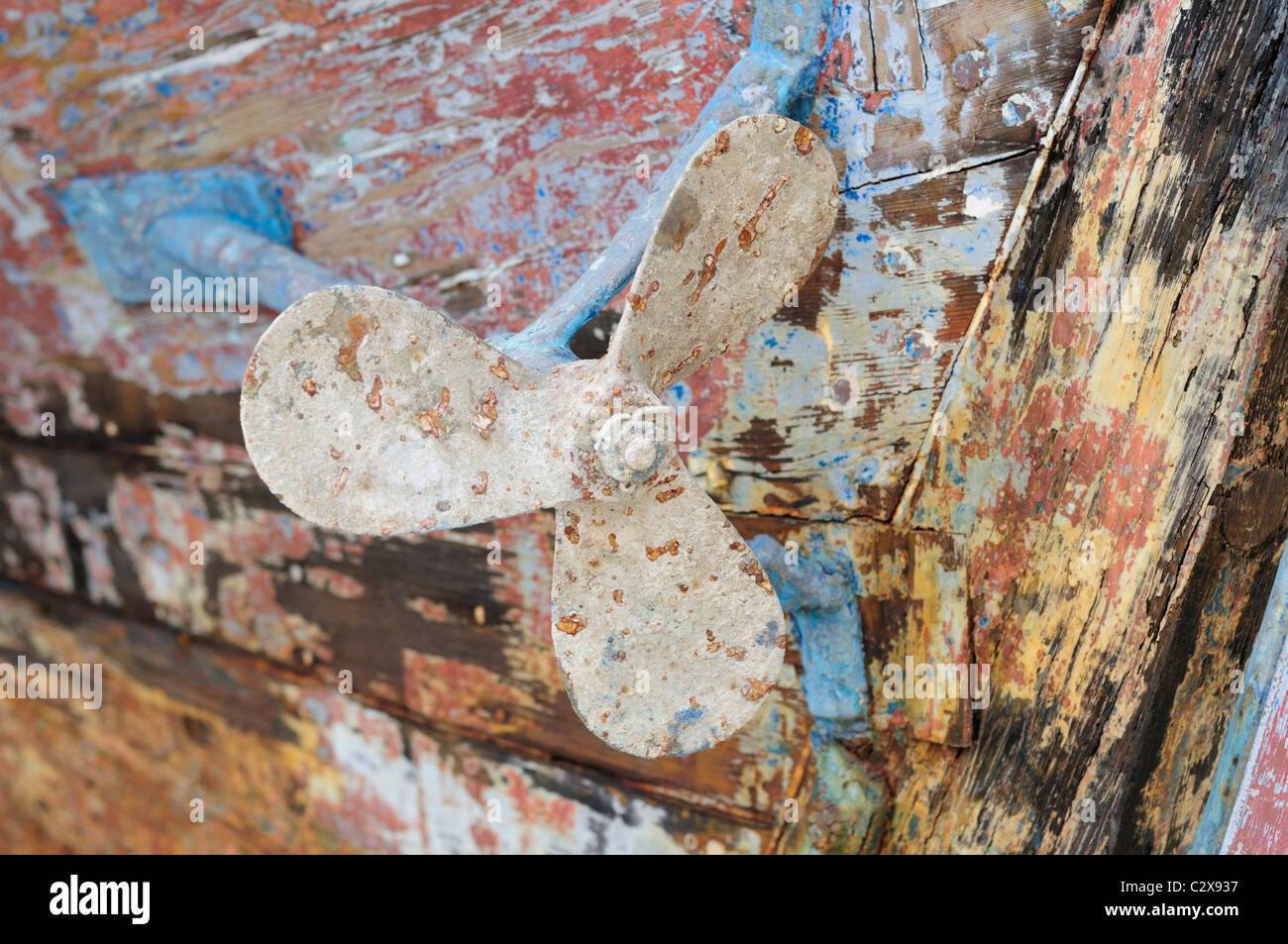 An old and worn propellor on the side of an old dilapidated boat's hull ...