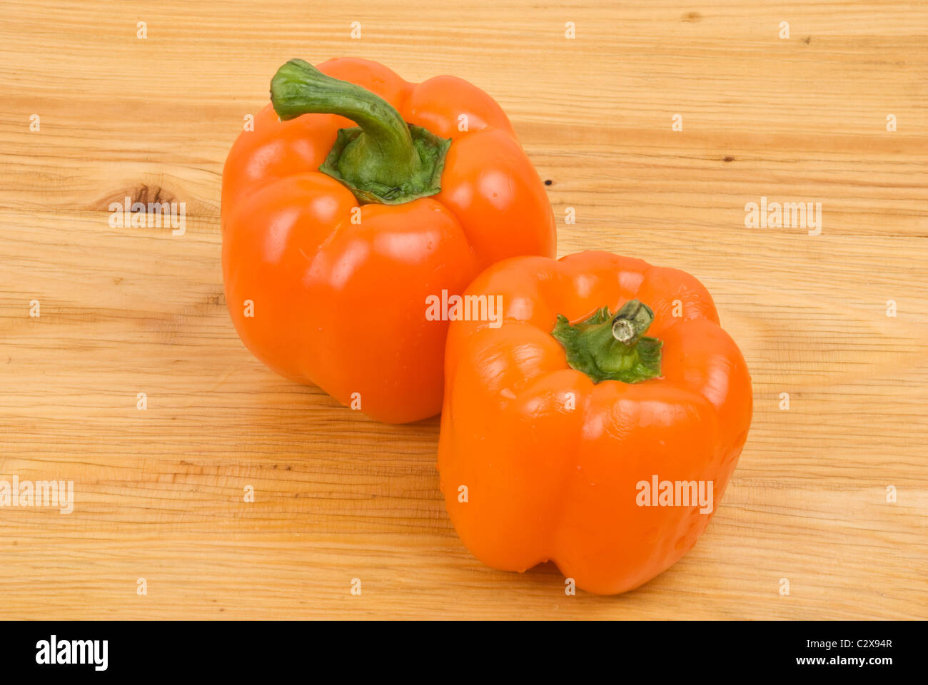 Two fresh orange capsicum on a wood table Stock Photo - Alamy