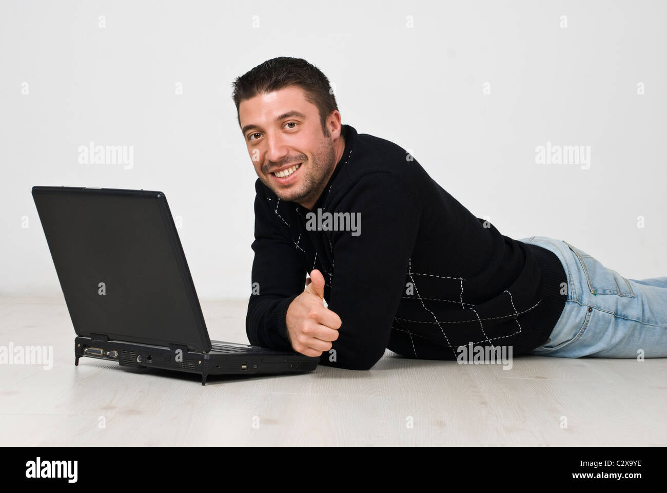 Successful happy man lying down o n floor using laptop and giving ...