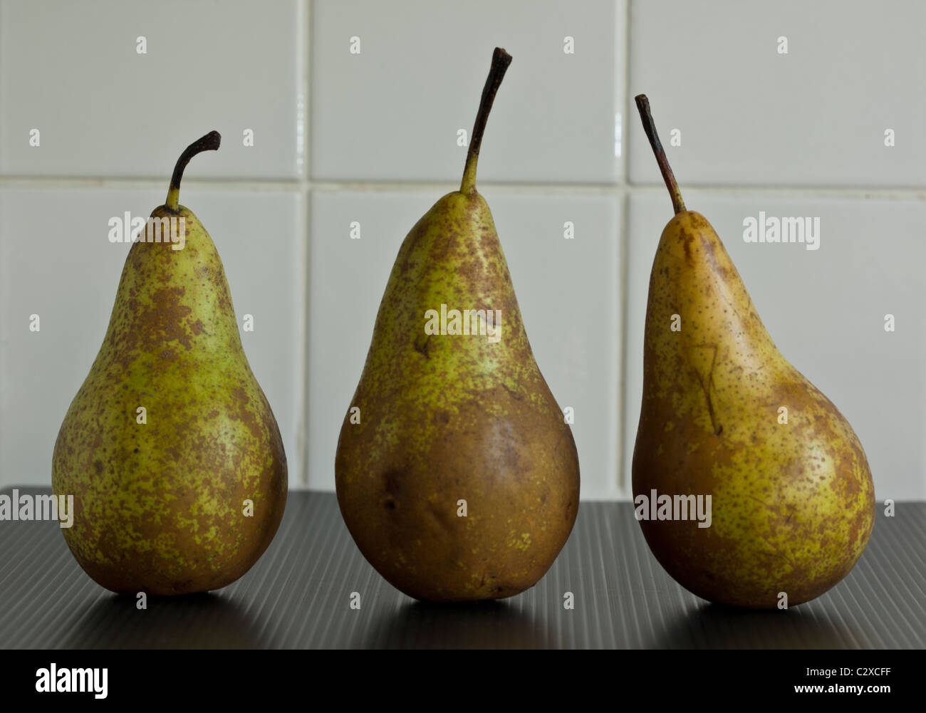 Three pears in front of white kitchen tiles Stock Photo - Alamy
