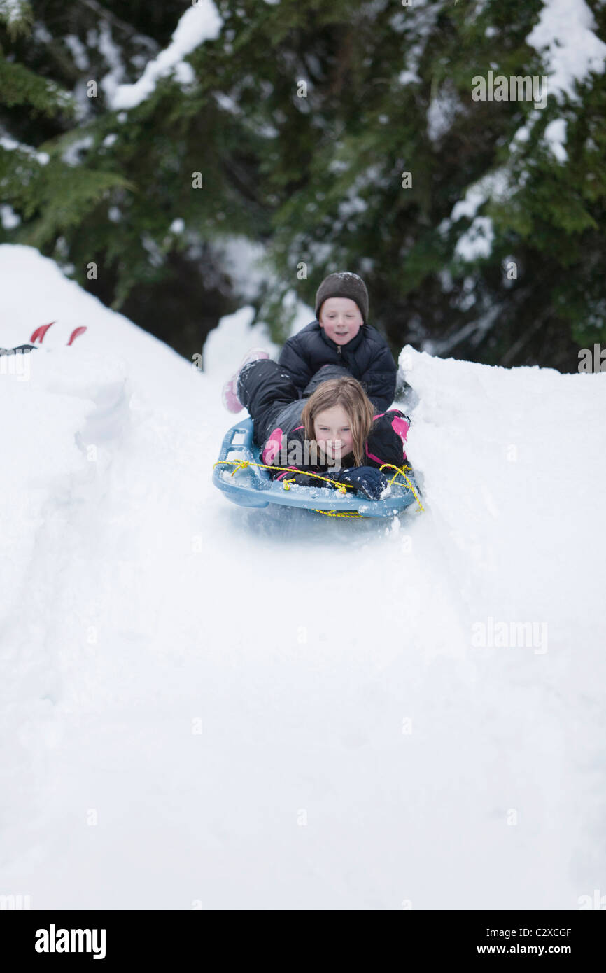 Caucasian children sledding in snow Stock Photo - Alamy