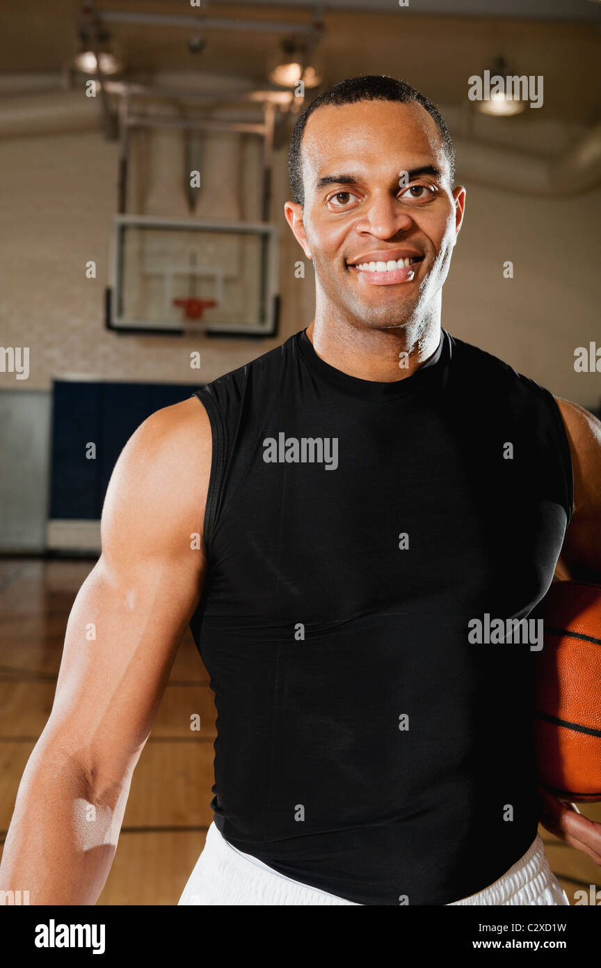 Mixed race man holding basketball on basketball court Stock Photo - Alamy