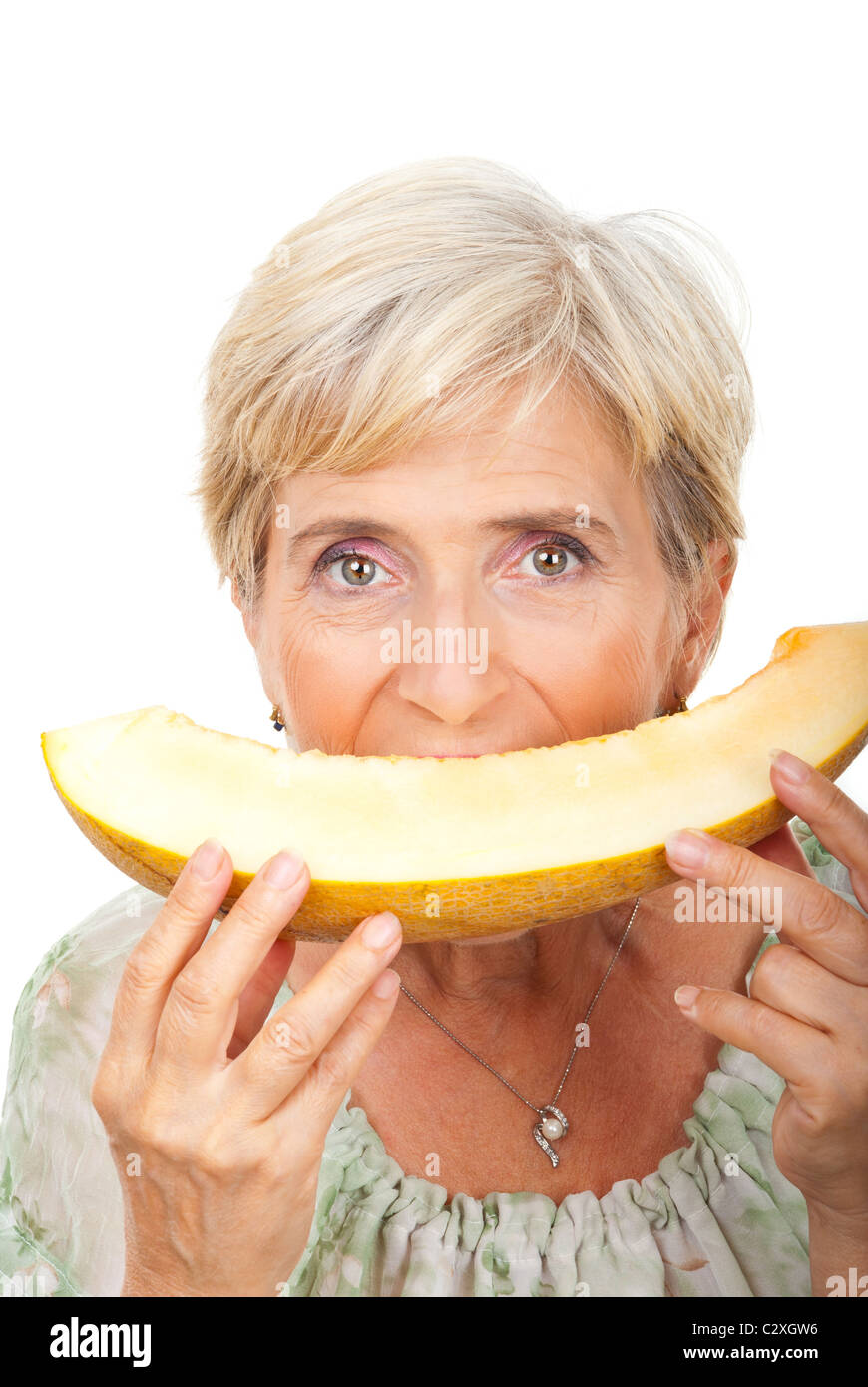 Senior woman eating a slice of melon in front of camera isolated on ...