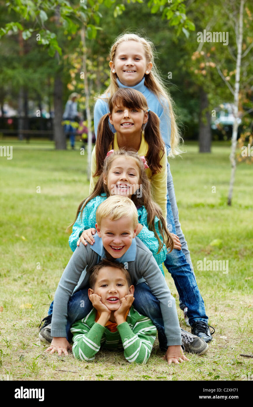 Portrait of happy friends lying on ground in park and looking at camera ...