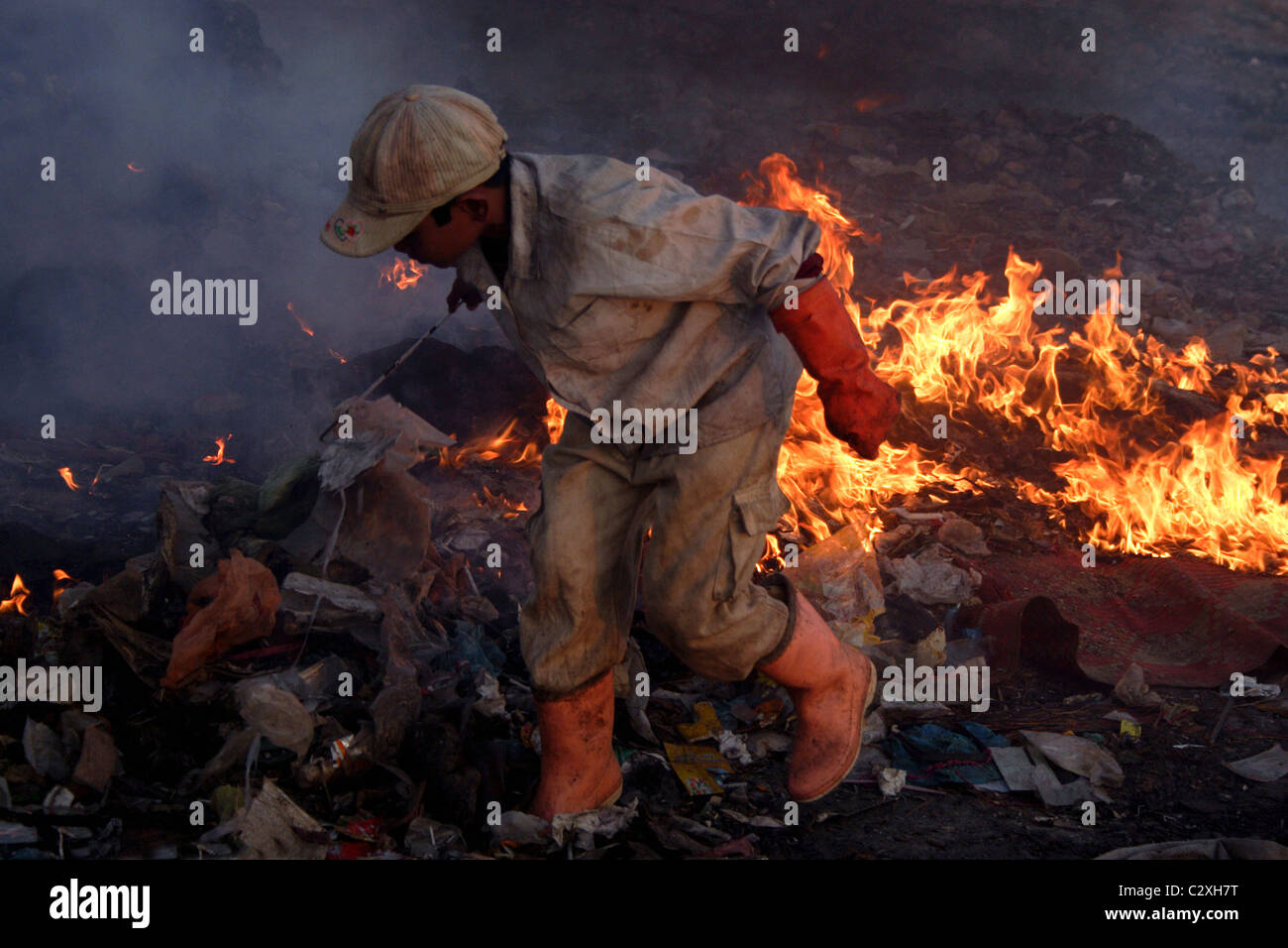 A young child laborer boy is running away from a pile of burning ...