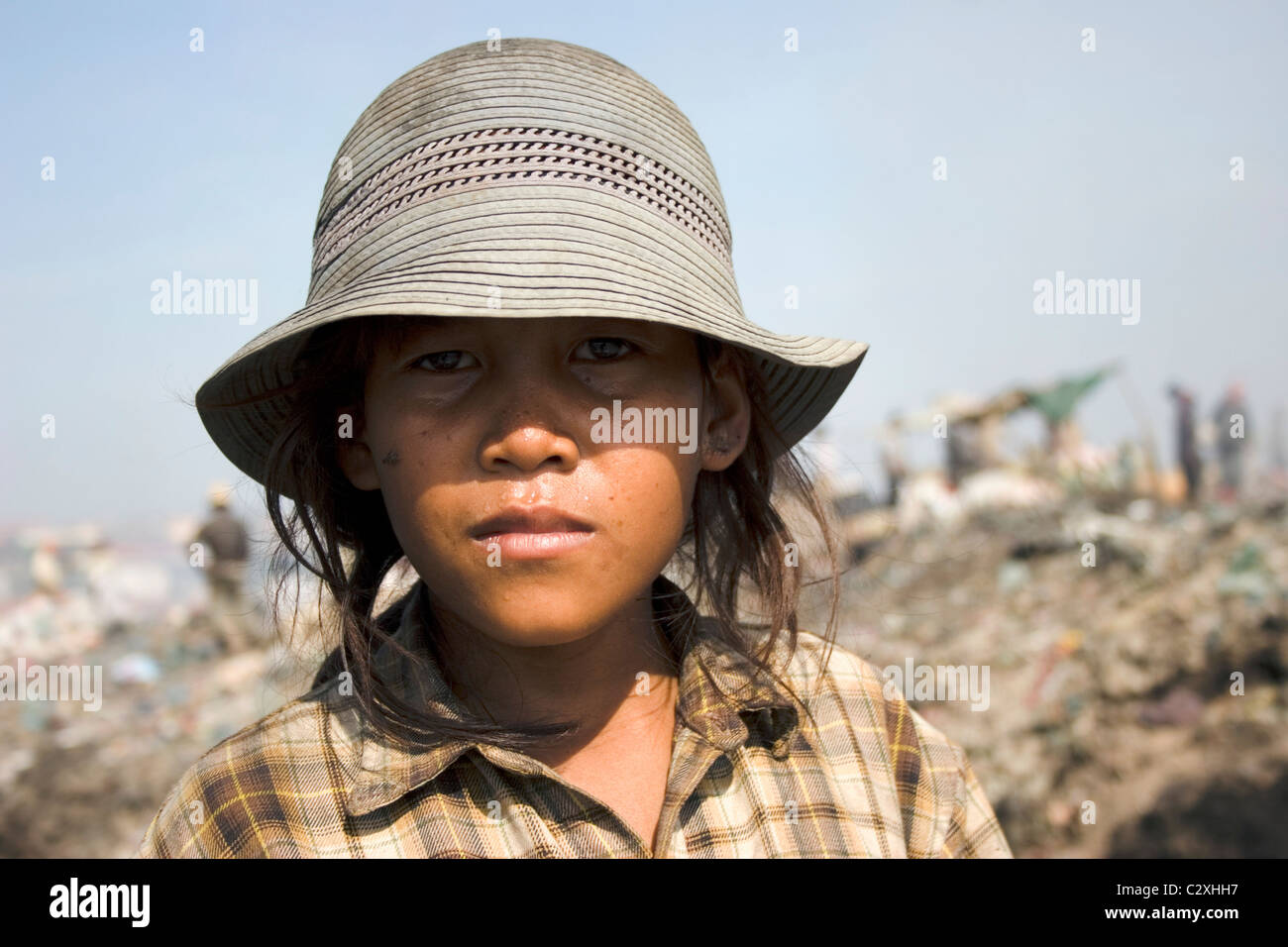 A young school aged child laborer girl is looking for recyclable ...