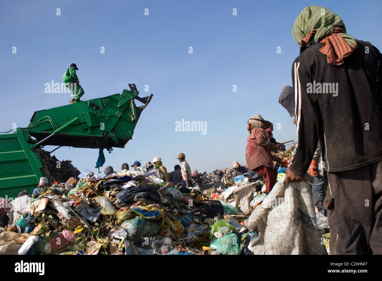 A worker is walking on top of a garbage truck at a toxic and polluted ...