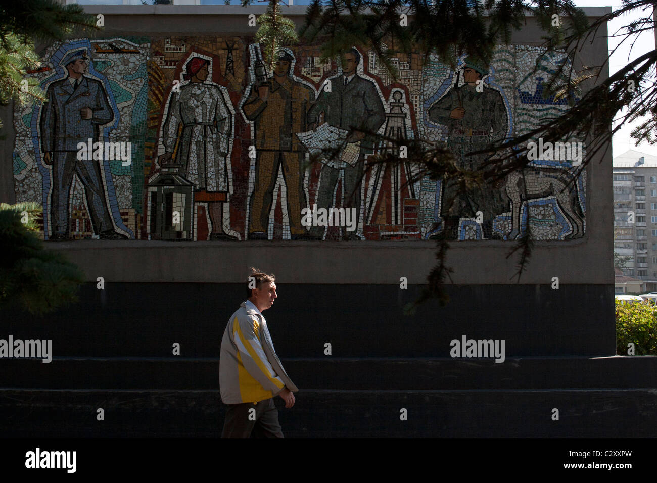 People walk by a Soviet era mural showing people of different ...