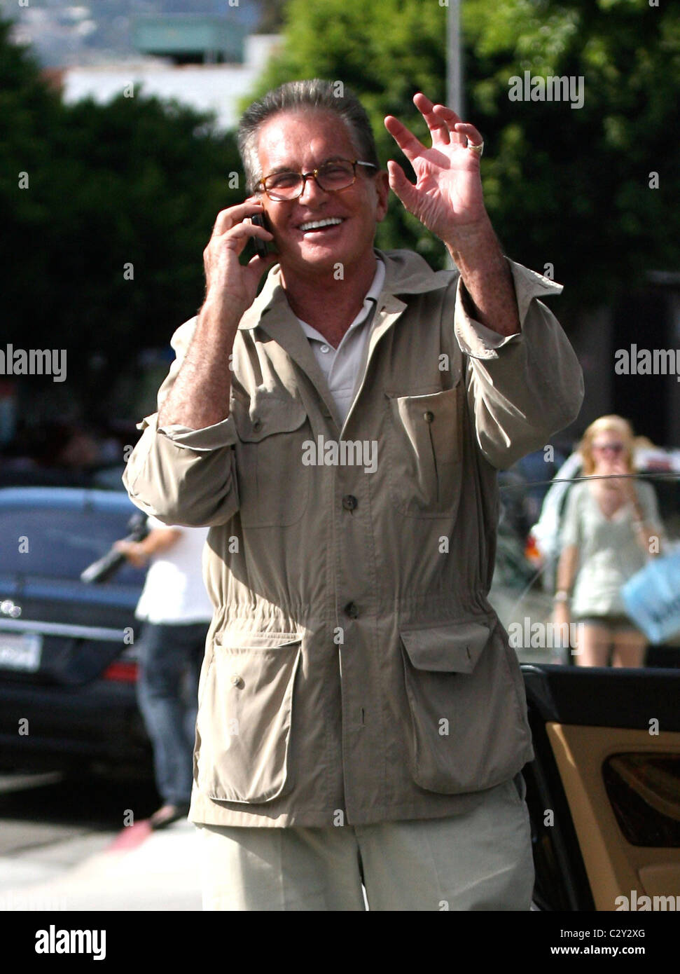 George Hamilton talks into his cellphone as he fills up his car with ...