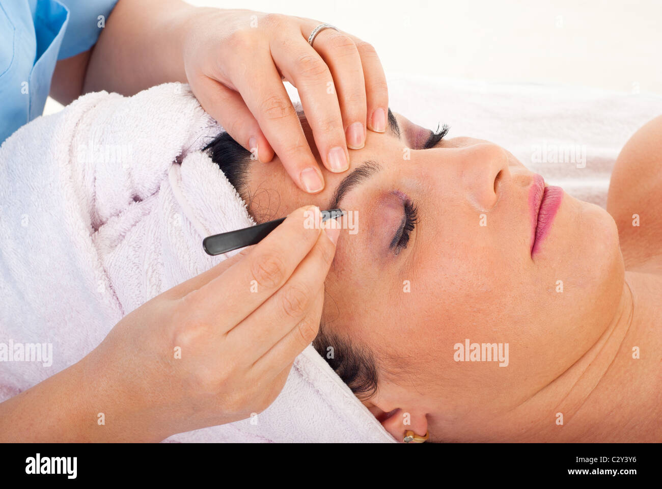 Close up of beautician hands plucking woman eyebrows in a spa retreat ...
