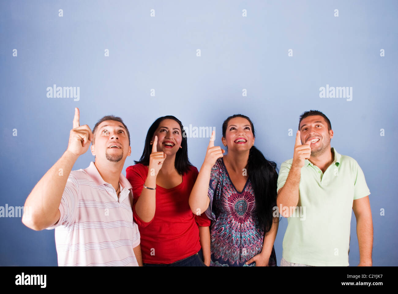 Happy group of people standing in a line, looking up and pointing ...