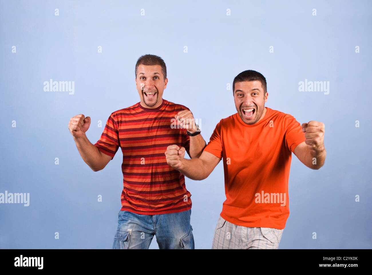 Yes!we won!Two excited guys standing and shooting with arms raised ...