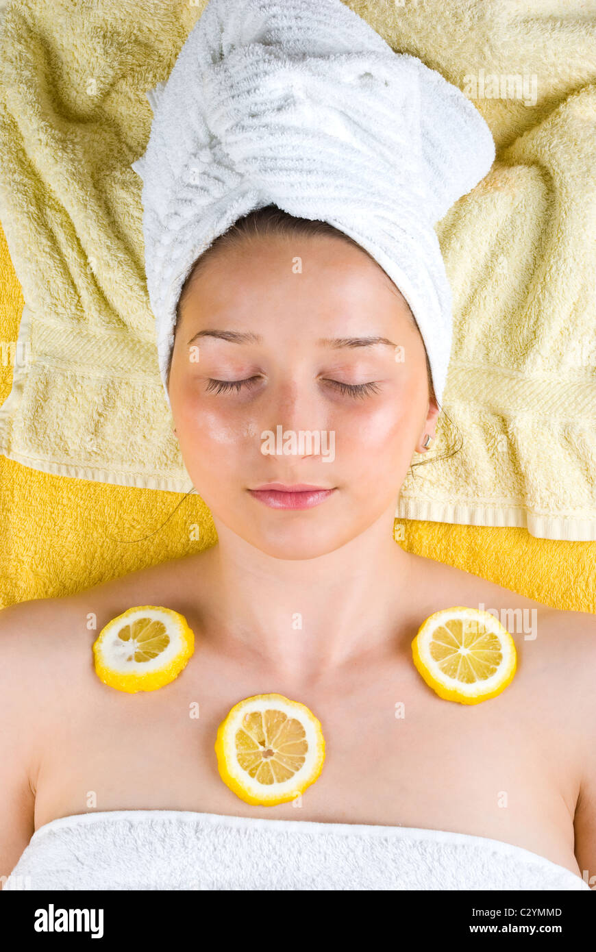 Young woman enjoying a therapy with slice lemon on her body skin at spa ...