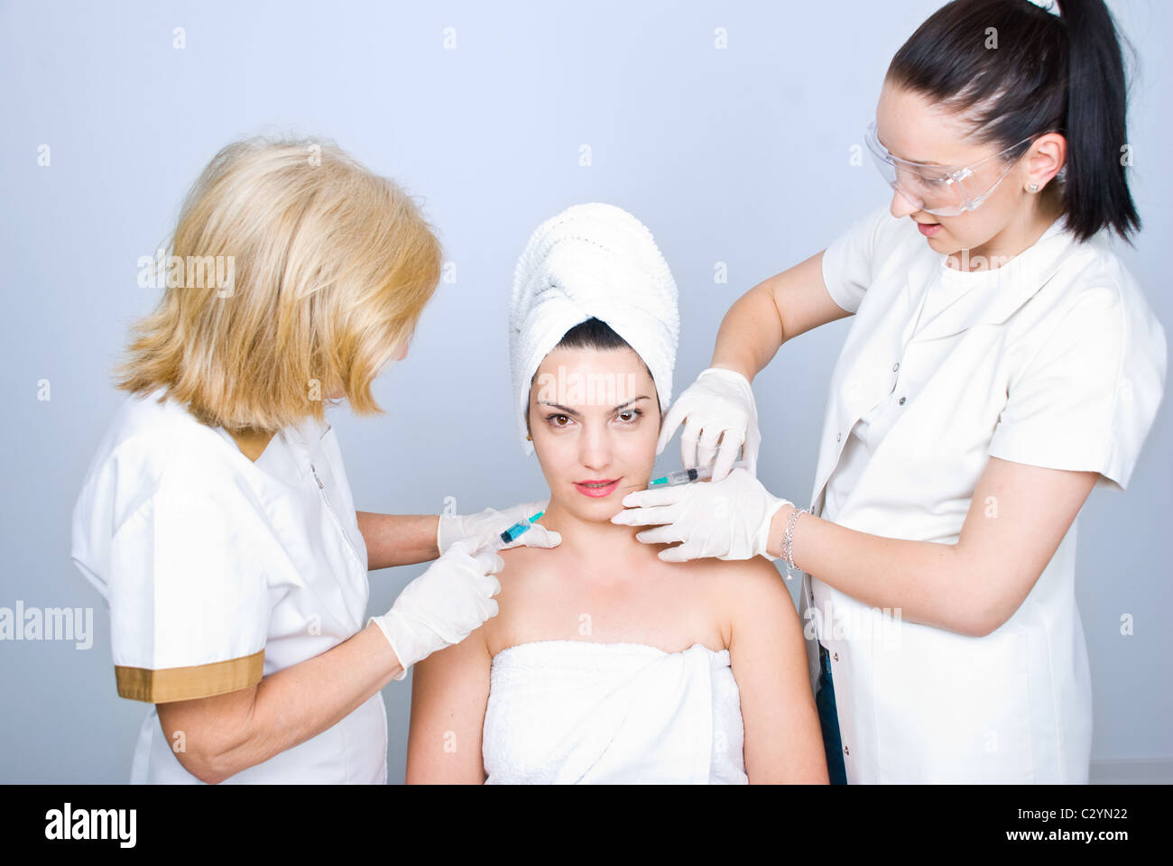 Two plastic surgeons giving botox injection to a young woman skin Stock ...