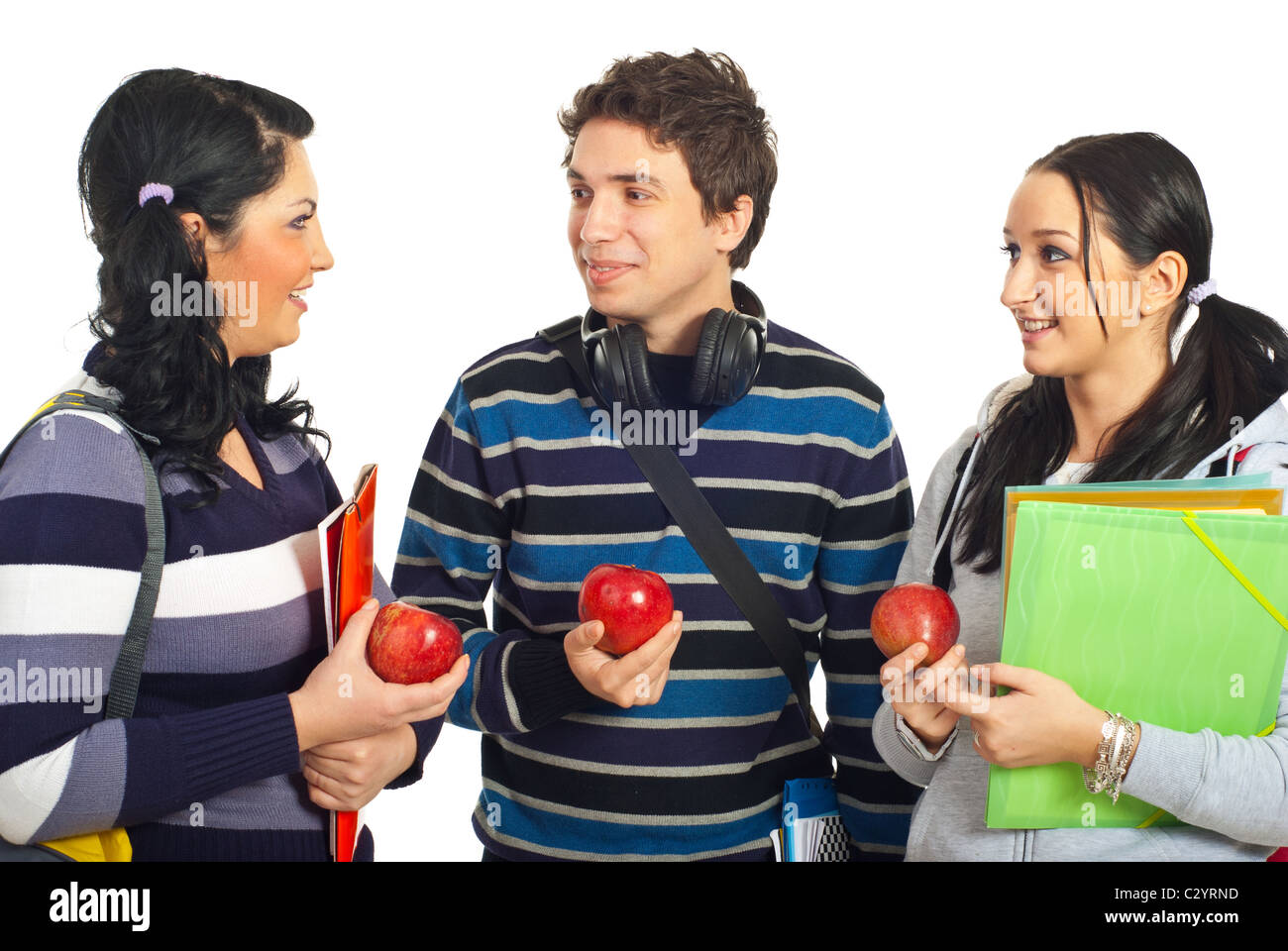 Three students holding notebooks and apples and having conversation ...