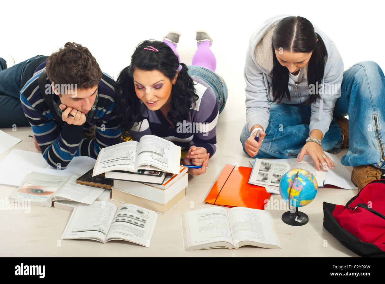 Three students sitting or lying on floor and studying together or doing ...